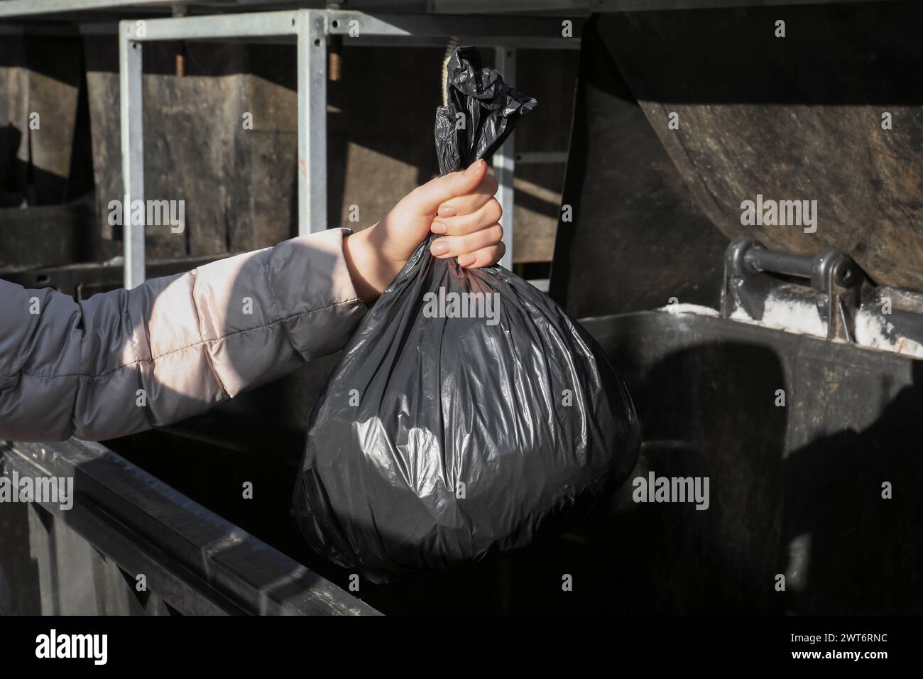 Woman throwing trash bag full of garbage in bin outdoors, closeup Stock ...