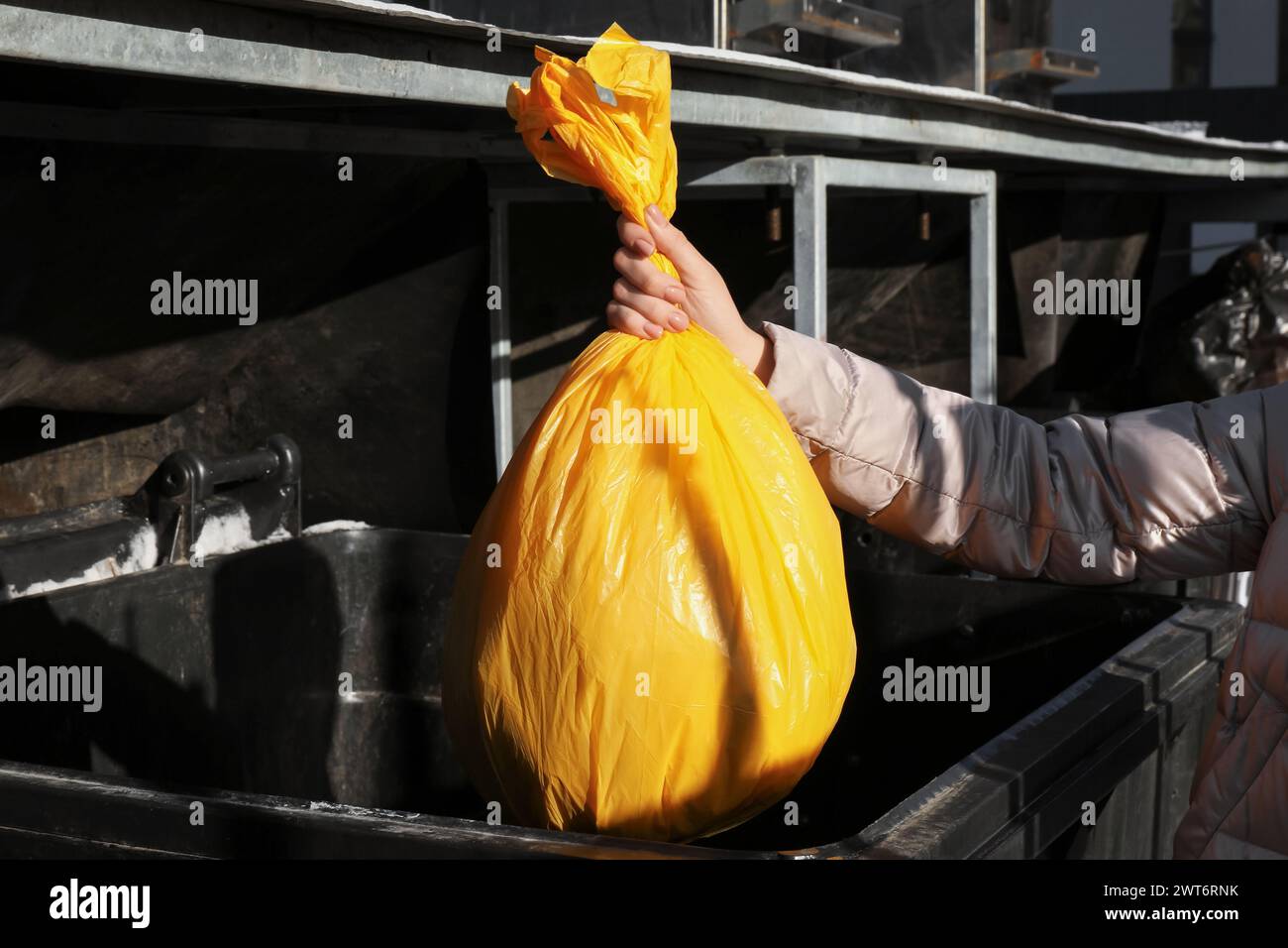 Woman throwing trash bag full of garbage in bin outdoors, closeup Stock ...