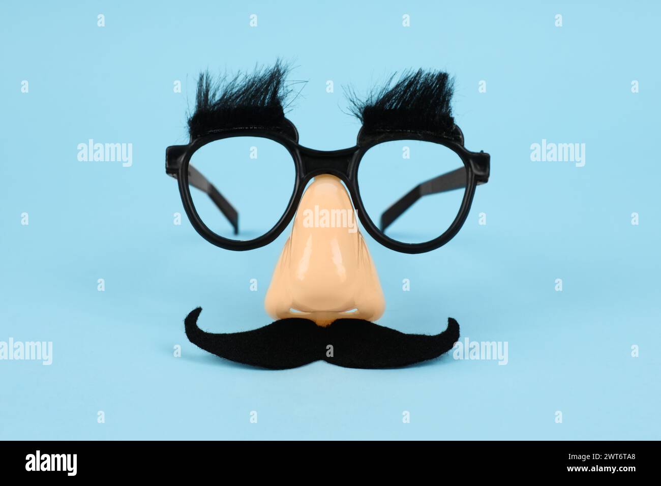 Funny mask with fake mustache, nose and glasses on light blue ...