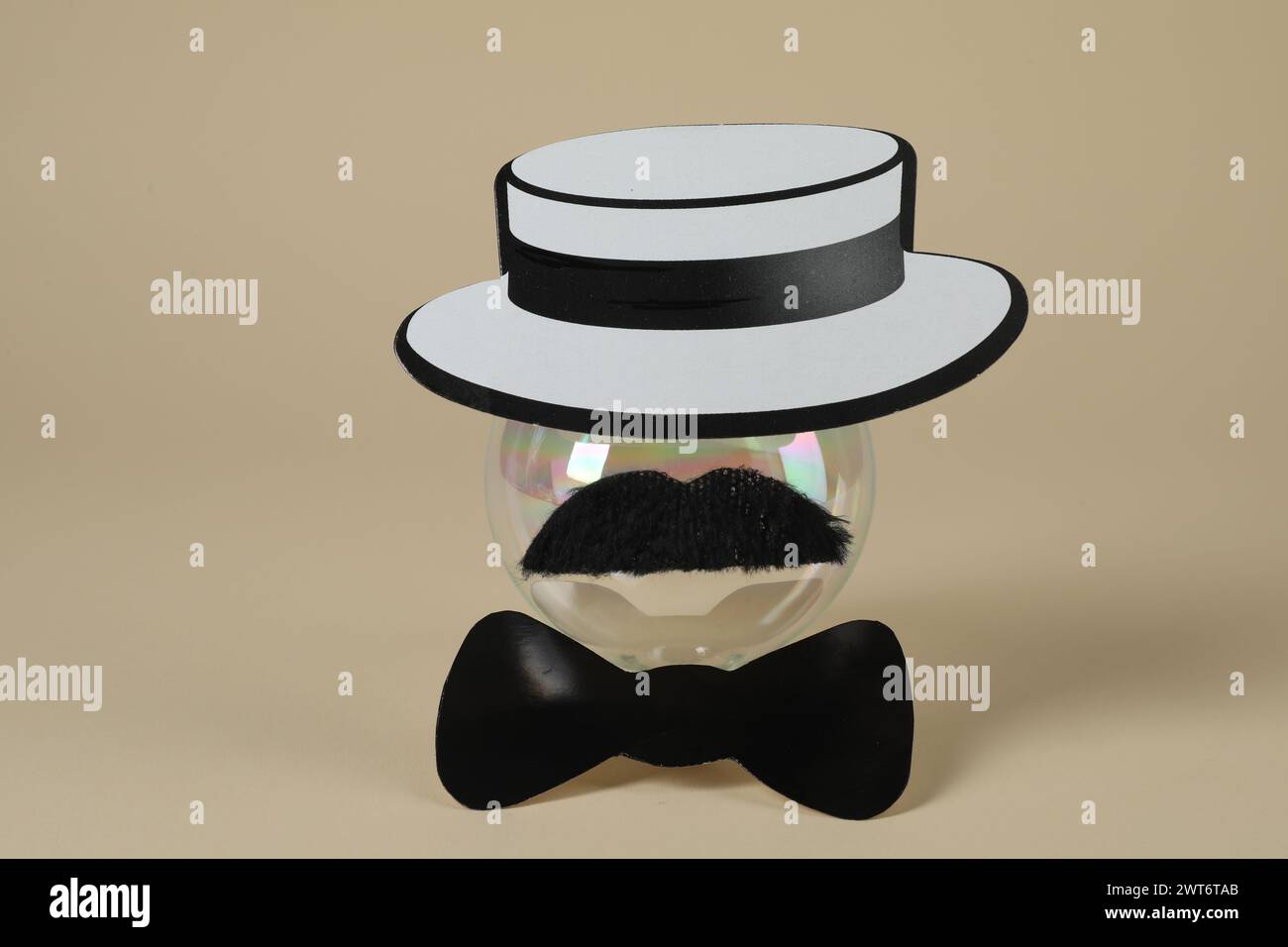 Man's face made of fake mustache, ball, hat and bow tie on beige ...