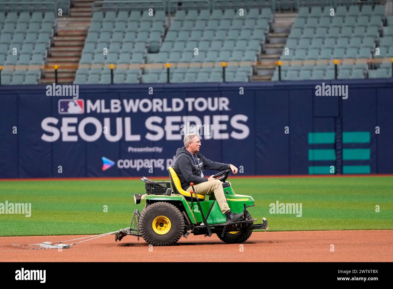A member of the grounds crew rakes the infield after the Los Angeles ...