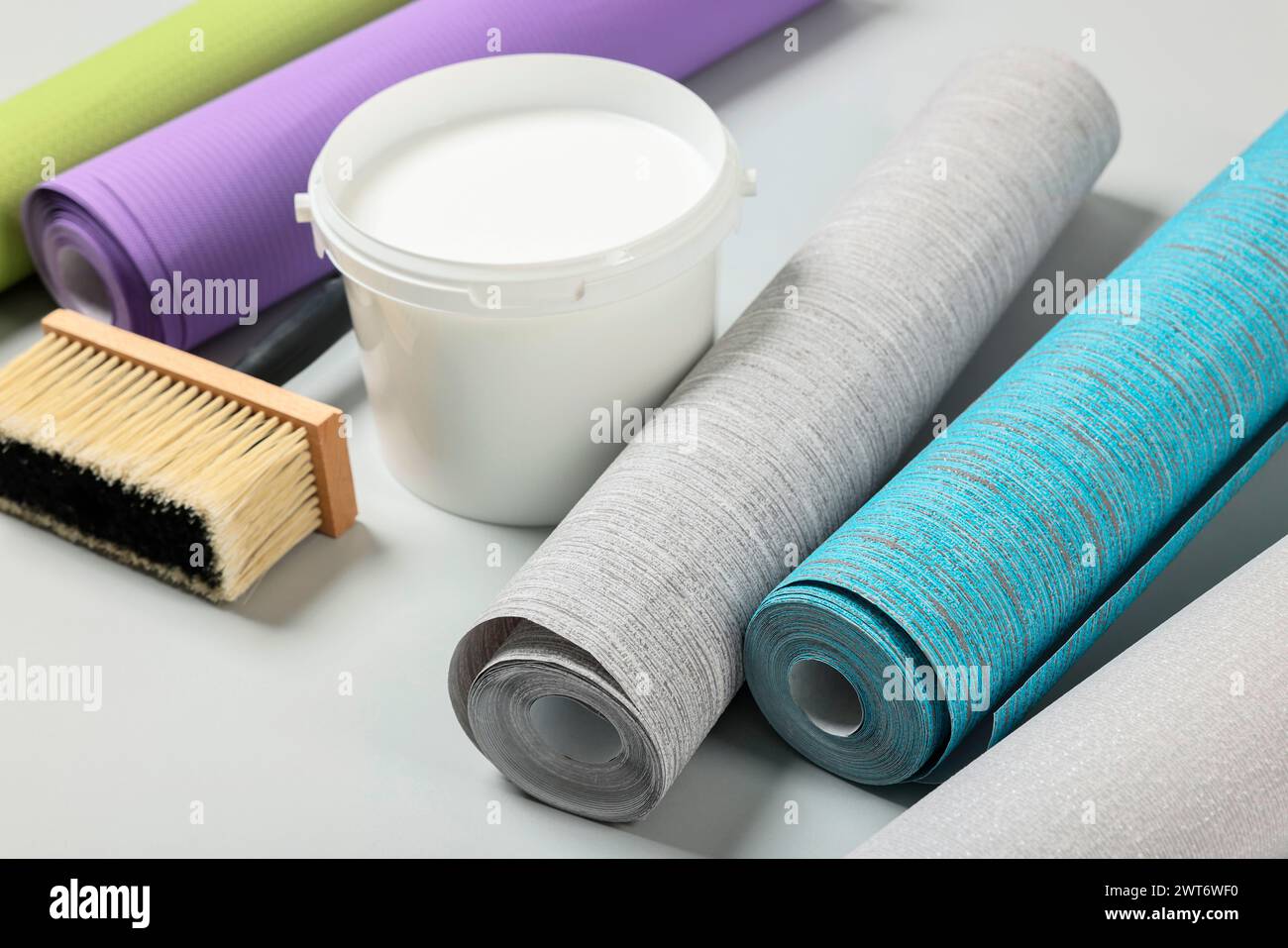 Different wallpaper rolls, brush and bucket with glue on light ...