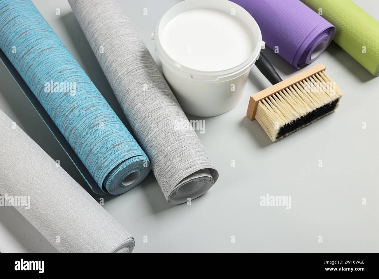 Different wallpaper rolls, brush and bucket with glue on light ...