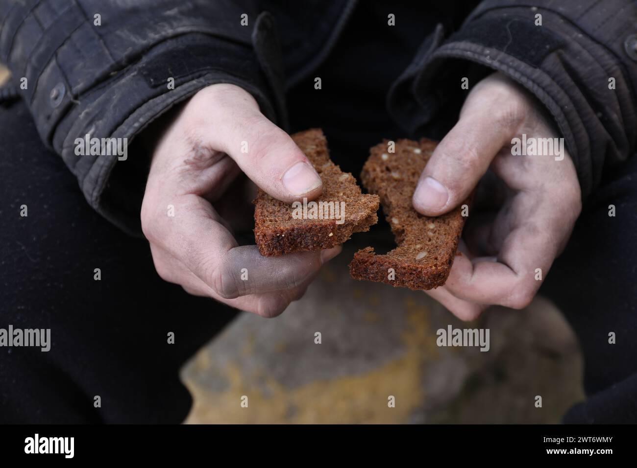 Poor homeless man holding piece of bread outdoors, closeup Stock Photo ...