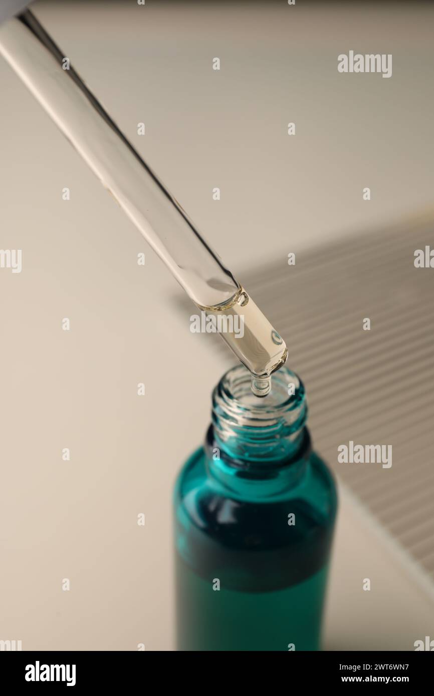 Dripping moisturizing serum from pipette into bottle on light ...