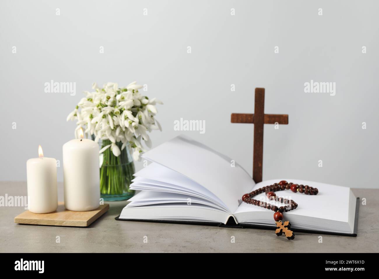 Church candles, Bible, wooden cross, rosary beads and flowers on grey ...