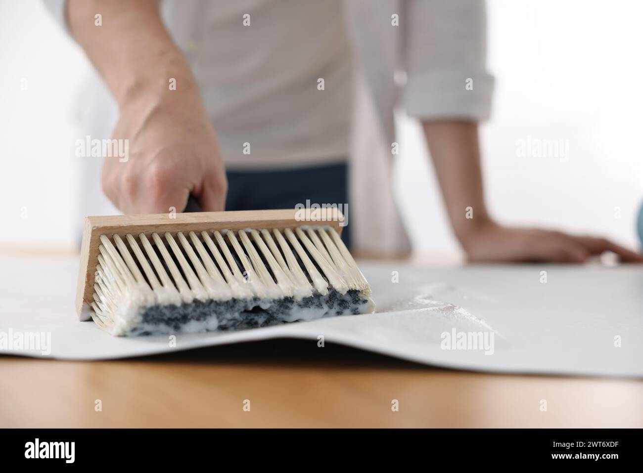 Man applying glue onto wallpaper sheet at table indoors, closeup Stock ...