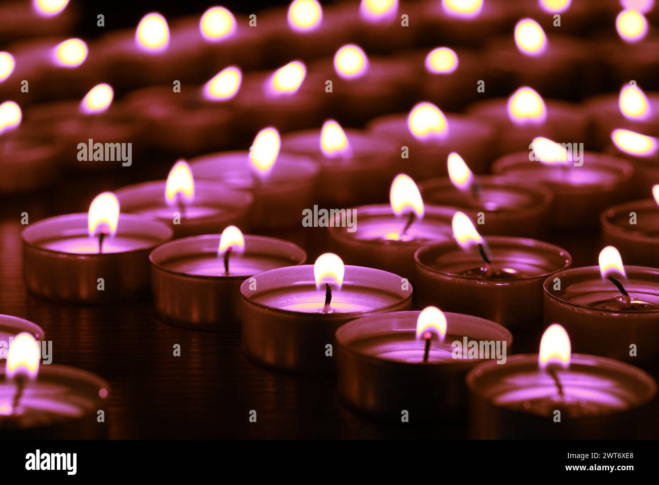 Beautiful burning violet candles on black background. Funeral ...