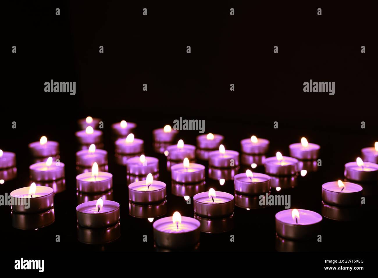 Beautiful burning violet candles on black background. Funeral ...
