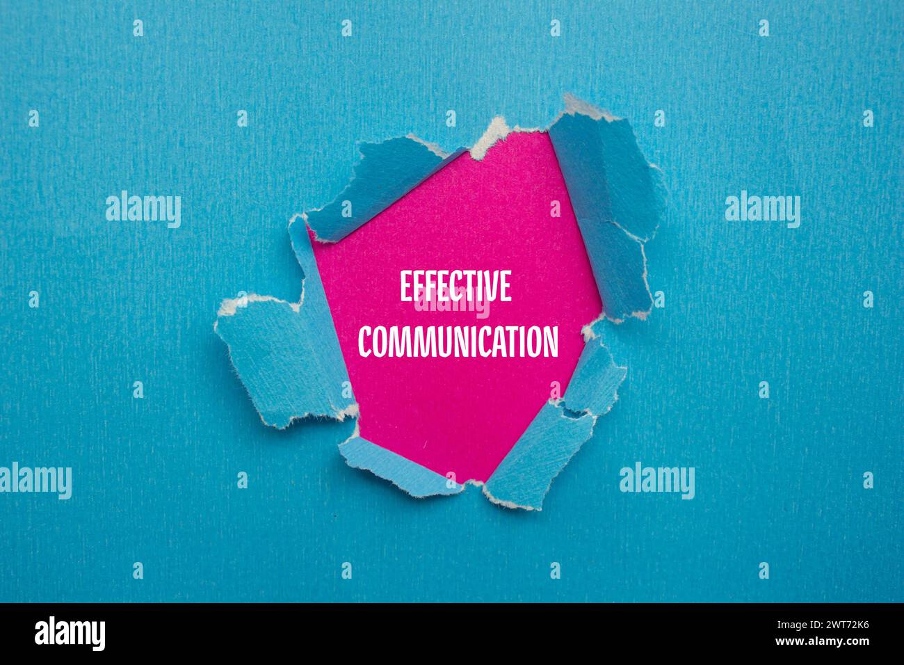 Effective communication words written on blue torn paper with pink ...
