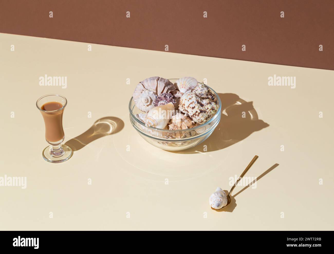 Summer scene made with glass bowl full of sea shells and cream liqueur ...