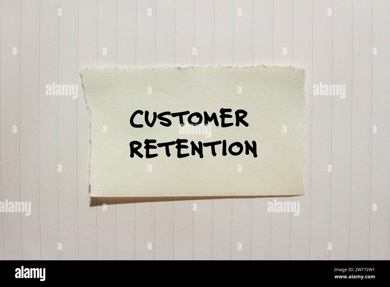 Customer retention words written on torn paper piece with notepad ...