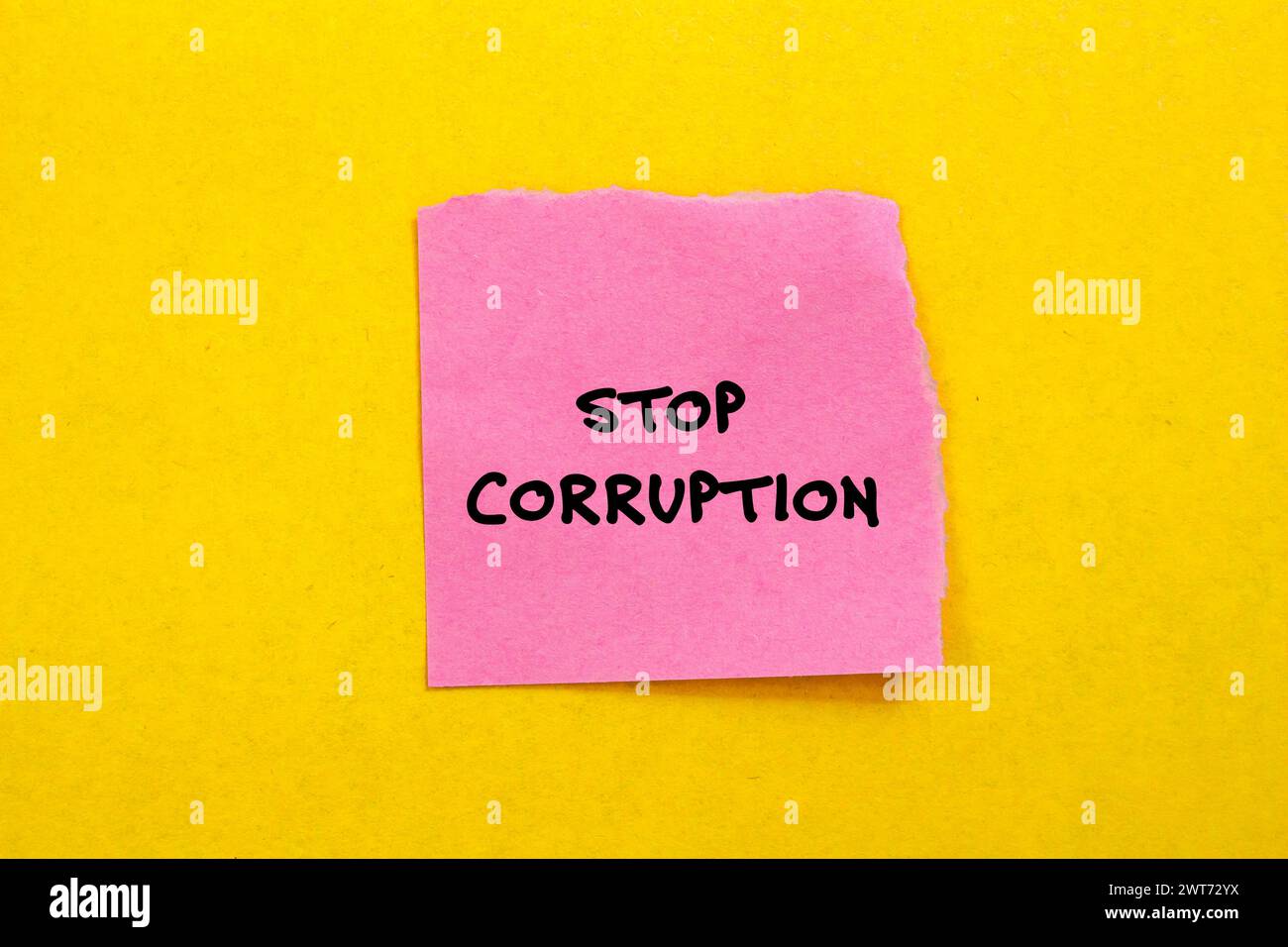 Stop corruption words written on pink torn paper with yellow background ...