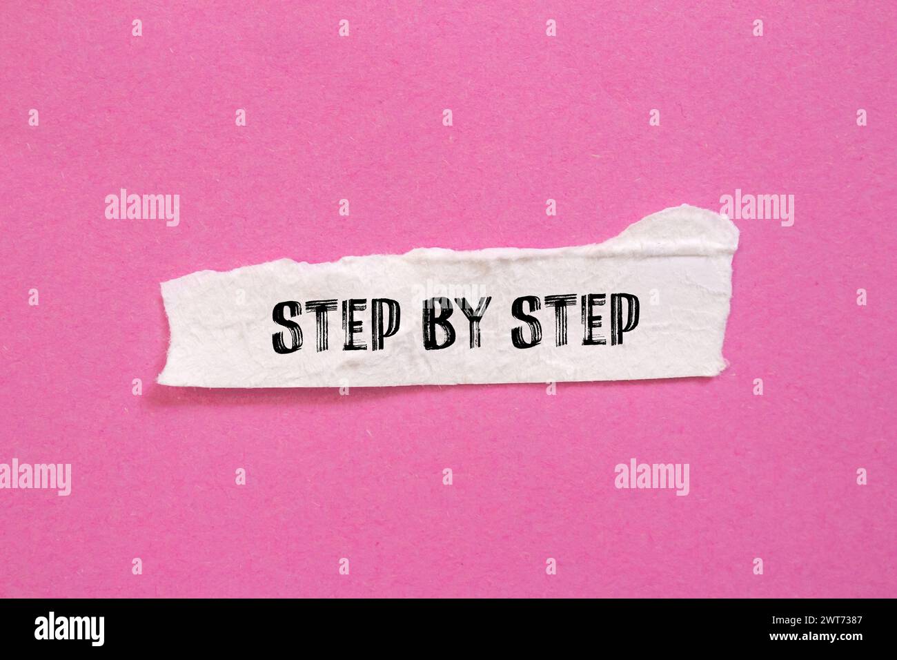Step by step words written on torn paper piece with pink background ...