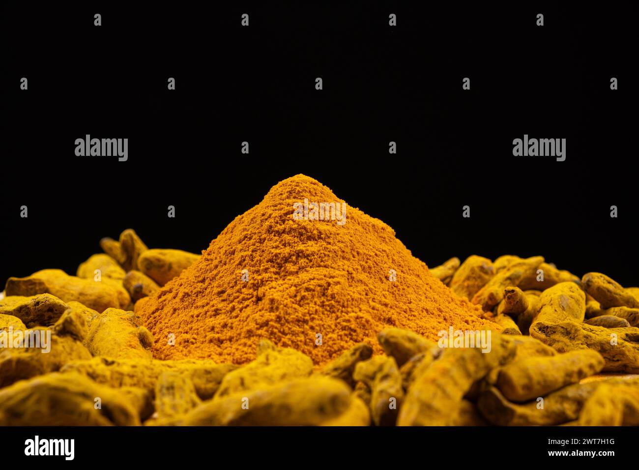 Turmeric powder and dried turmeric root on a black background Stock ...