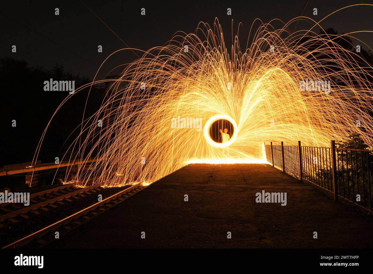 Spinning the steel wool on railway station platform. Sparks flying out ...