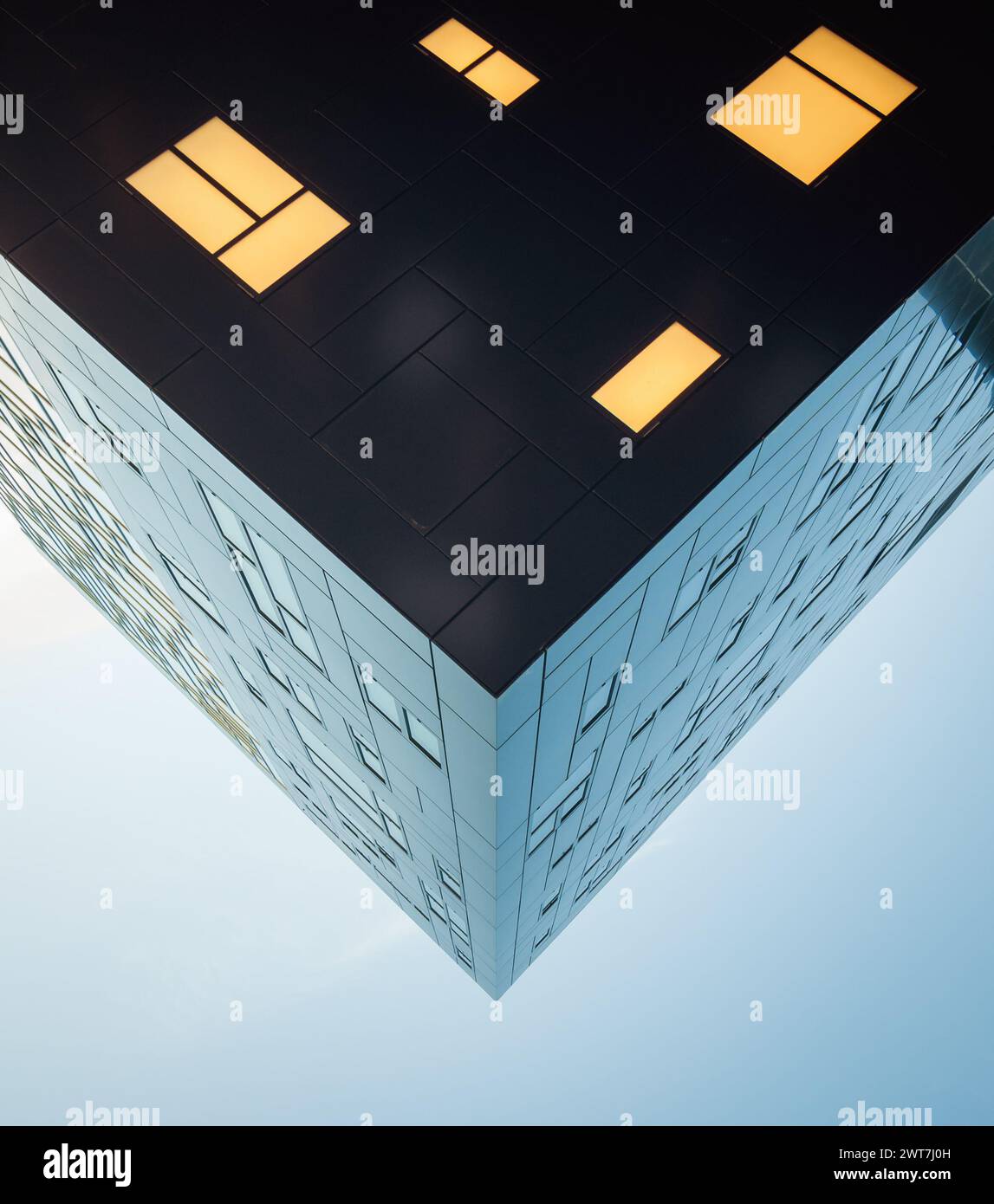 Corner of modern building overhang with yellow lights in it. Clear blue ...