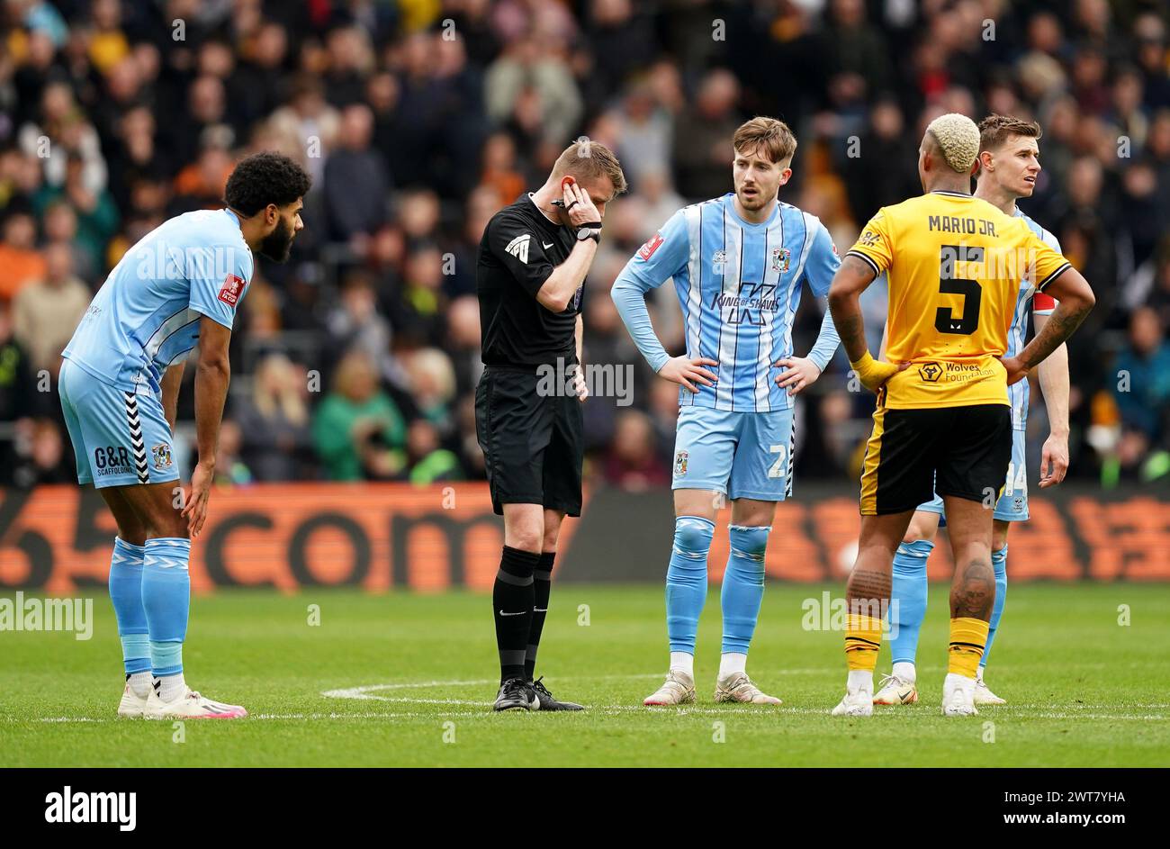 Referee Samuel Barrott and the players stand waiting for the VAR review ...