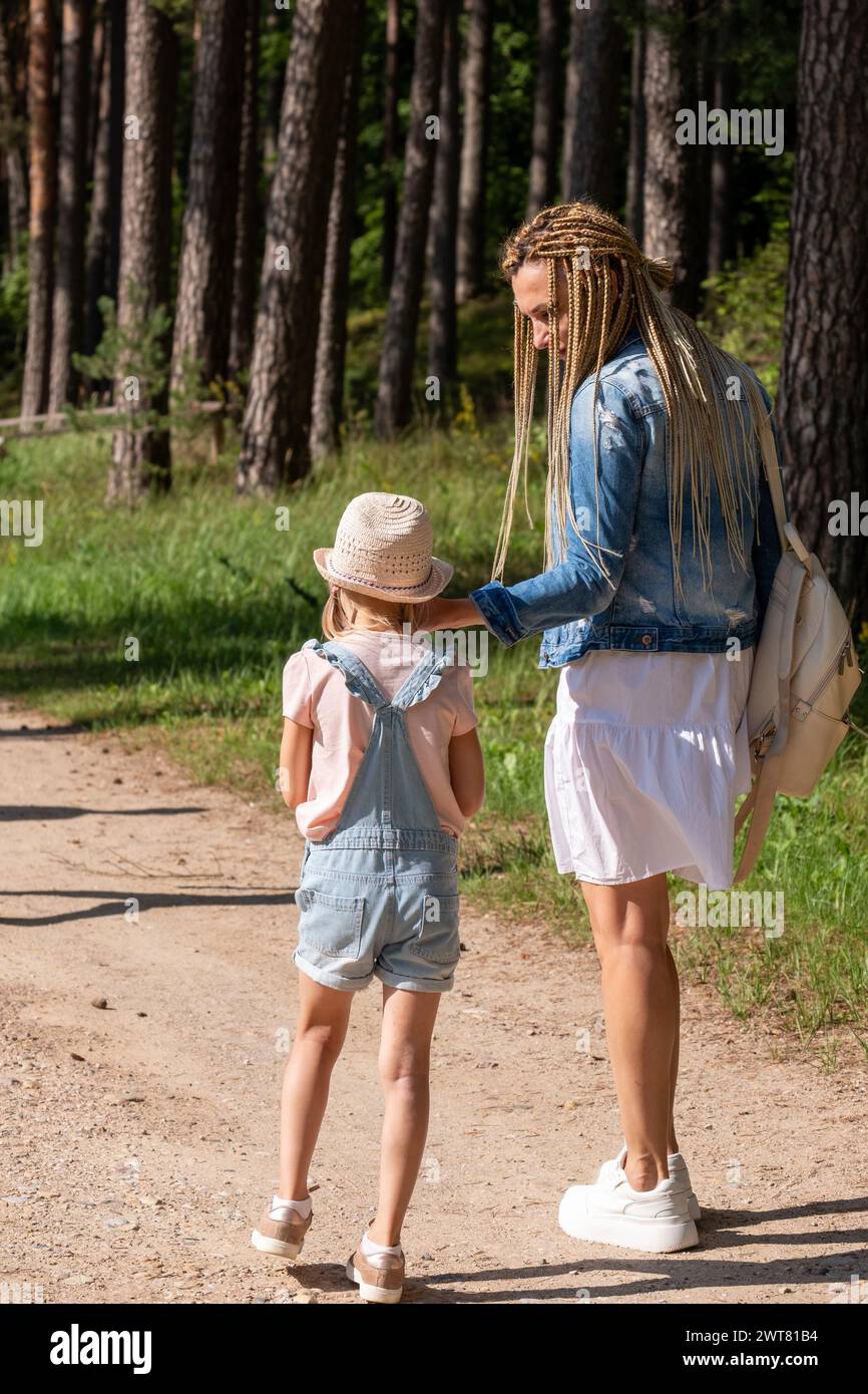 A woman, mother, guides her child a little girl on a woodland path, a ...