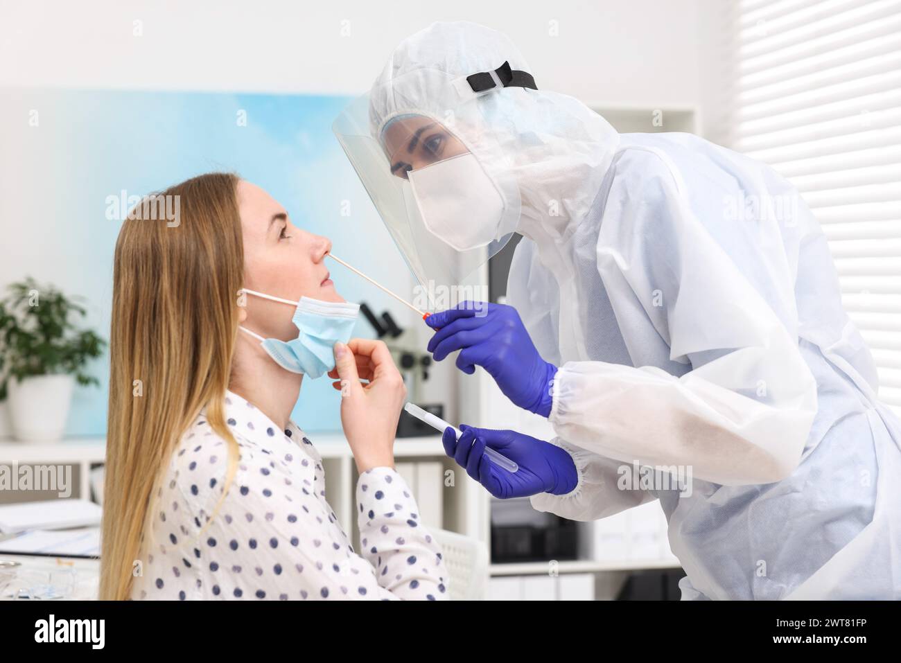 Laboratory testing. Doctor in uniform taking sample from patient's nose ...
