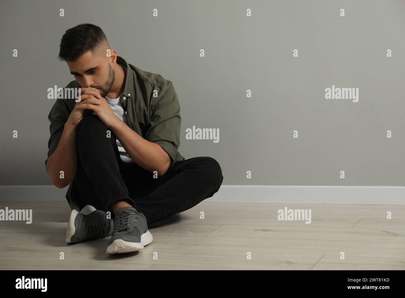 Sad man sitting on floor near light grey wall. Space for text Stock ...
