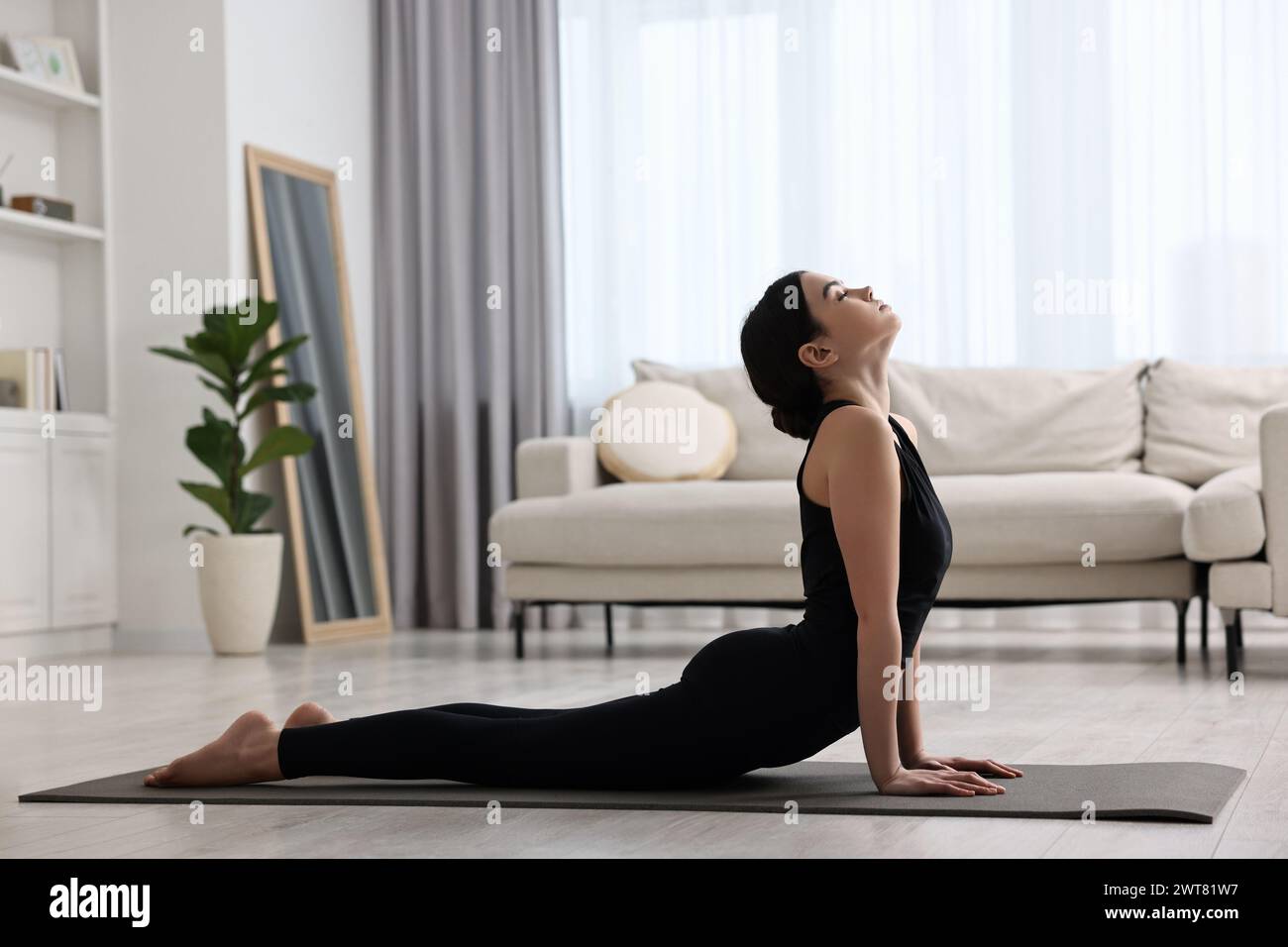 Girl practicing cobra asana on yoga mat at home. Bhujangasana pose ...