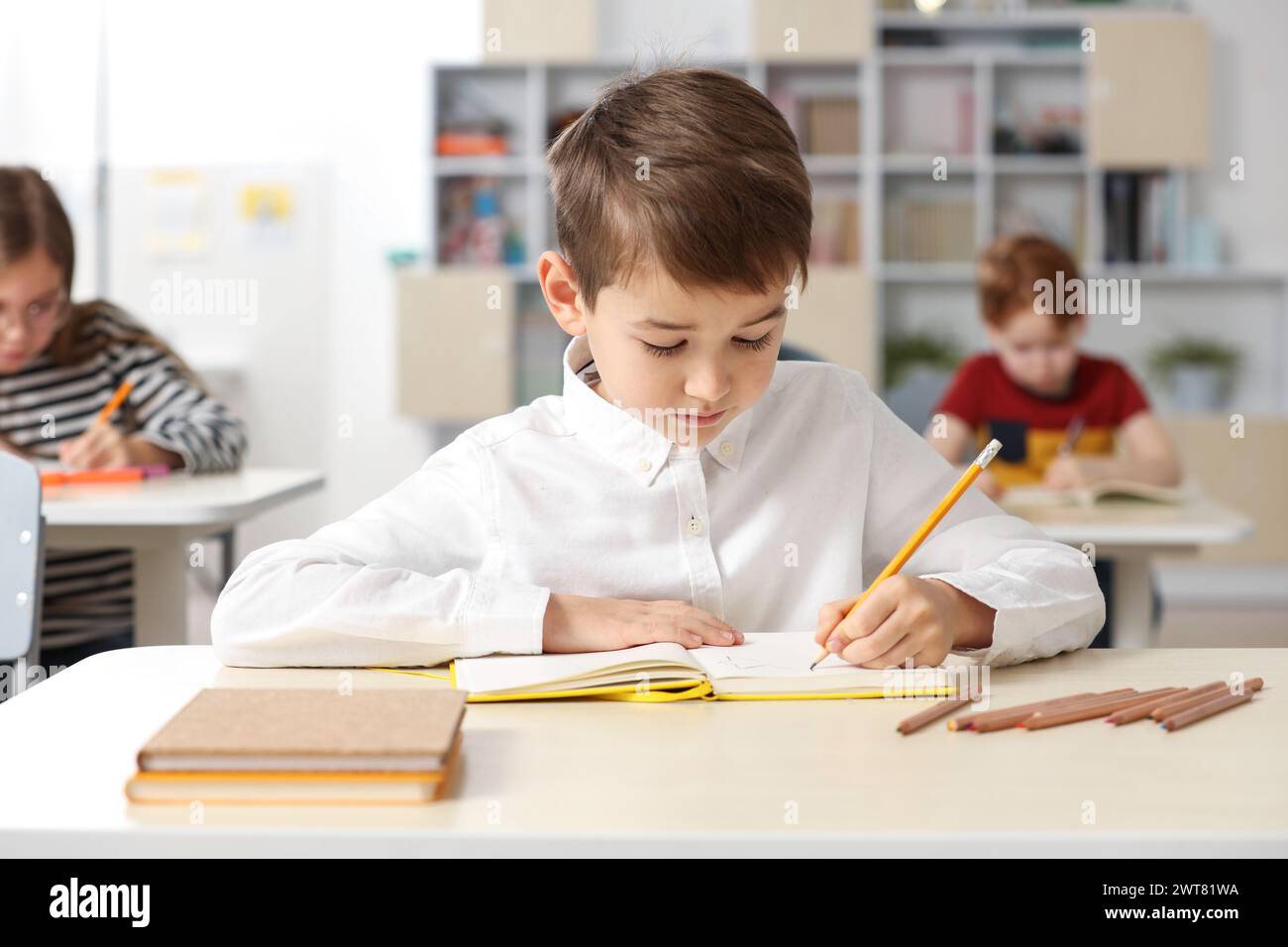 Portrait of cute little boy studying in classroom at school Stock Photo ...