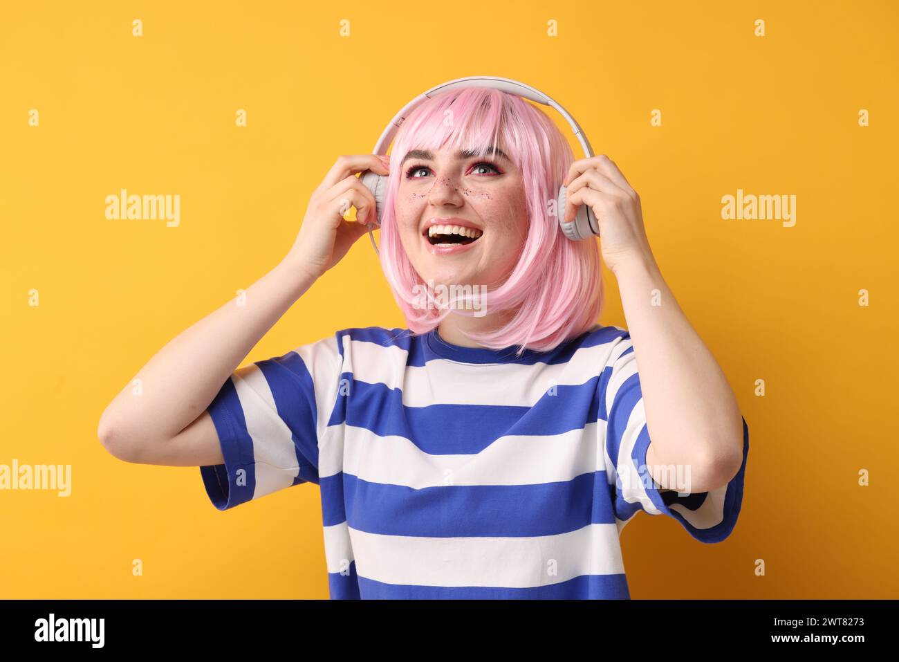 Happy woman with bright makeup and glitter freckles listening to music ...