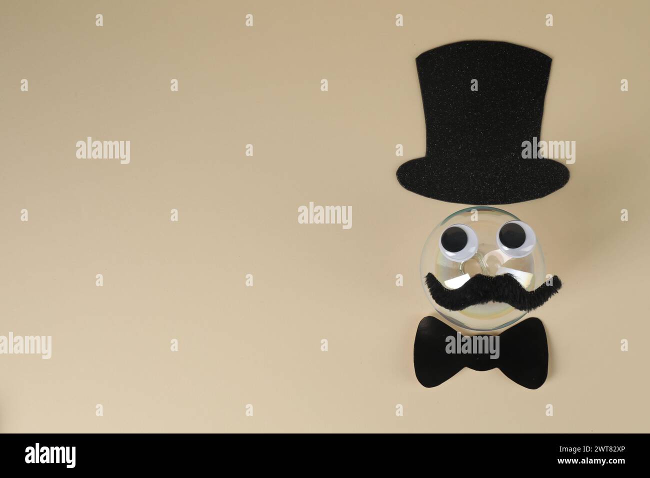 Man's face made of fake mustache, ball, hat, bow tie and eyes on beige ...
