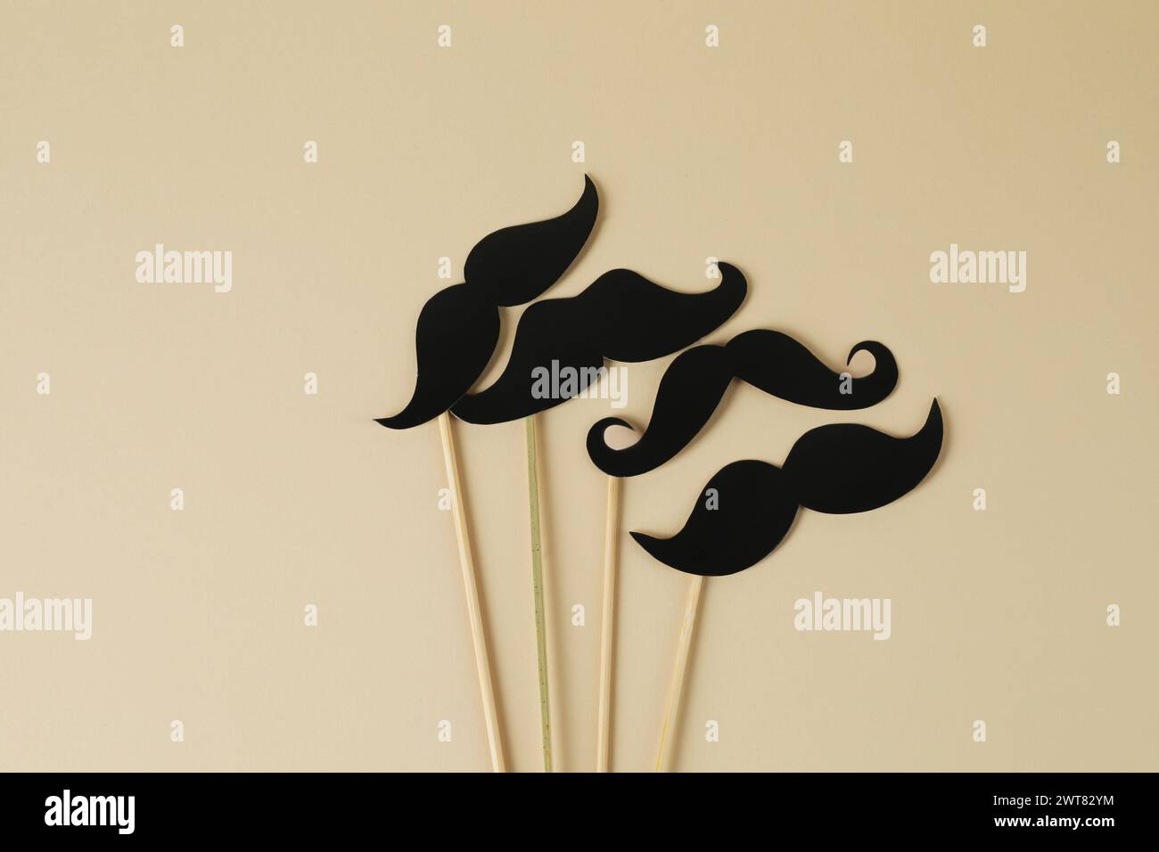 Fake paper mustaches party props on beige background, flat lay. Space ...
