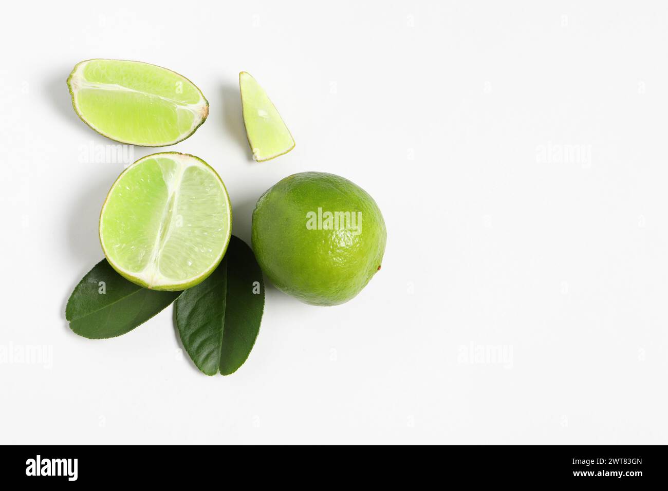 Fresh ripe limes and leaves on white background, flat lay. Space for ...