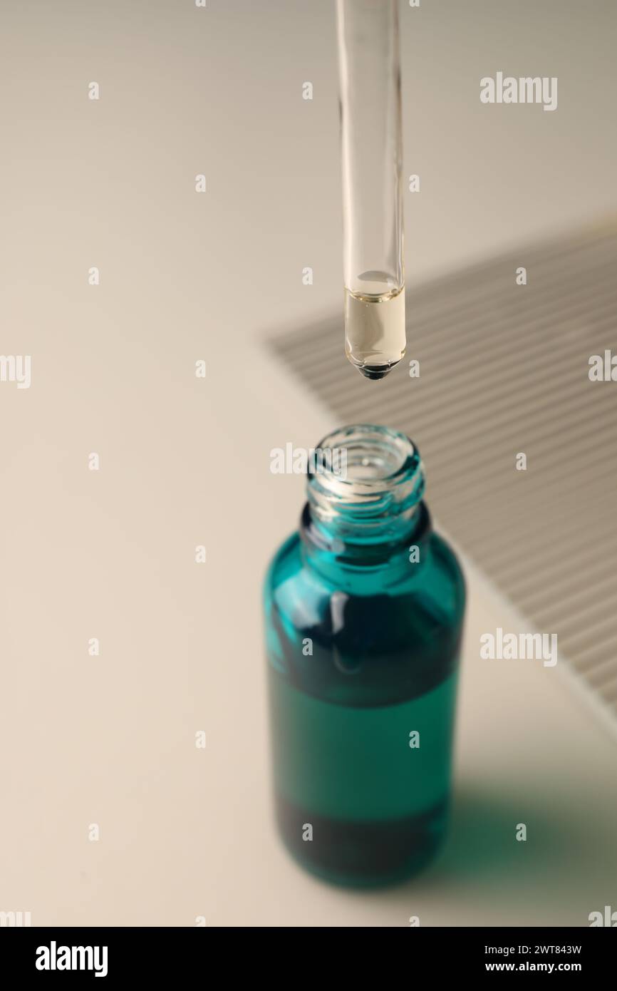 Dripping moisturizing serum from pipette into bottle on light ...