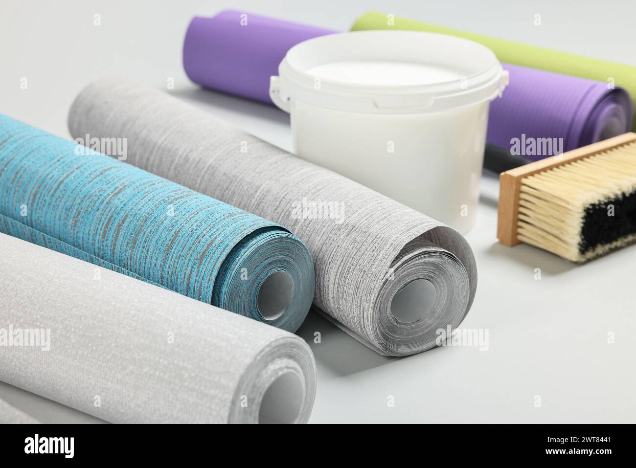 Different wallpaper rolls, brush and bucket with glue on light ...