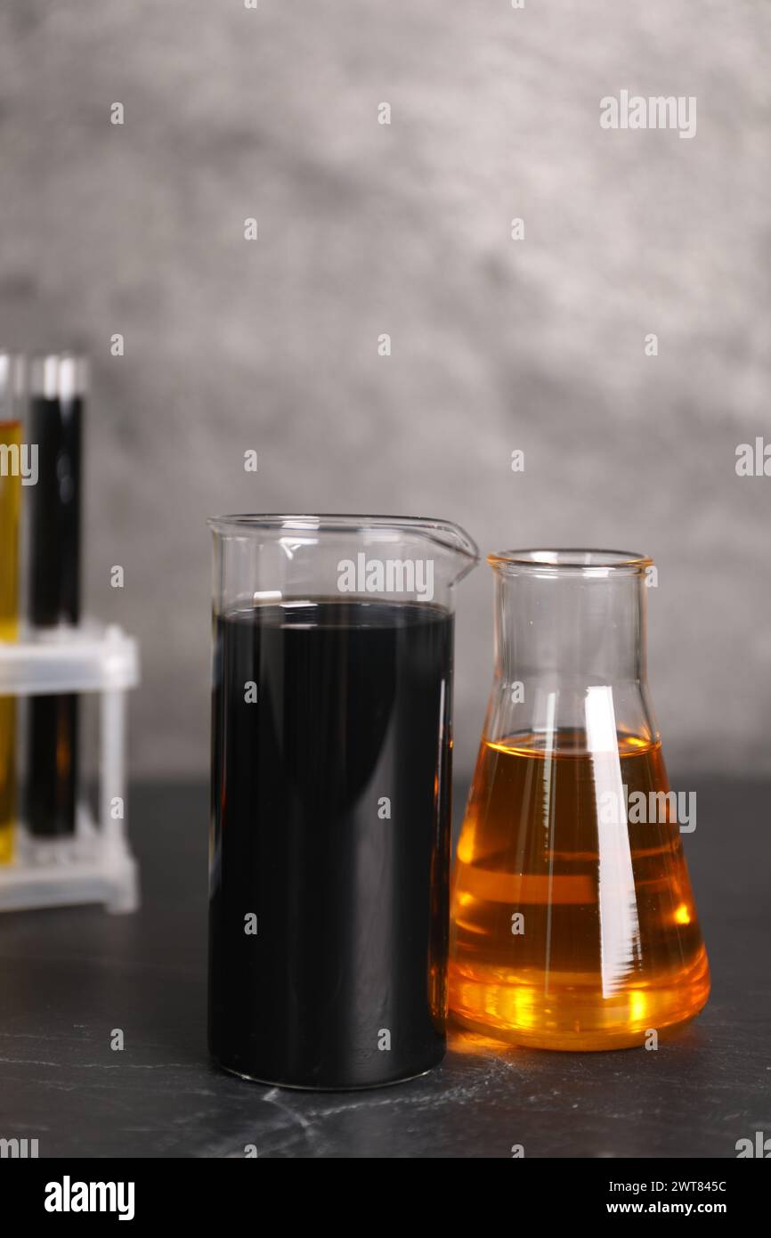 Beaker, flask and test tubes with different types of oil on grey ...