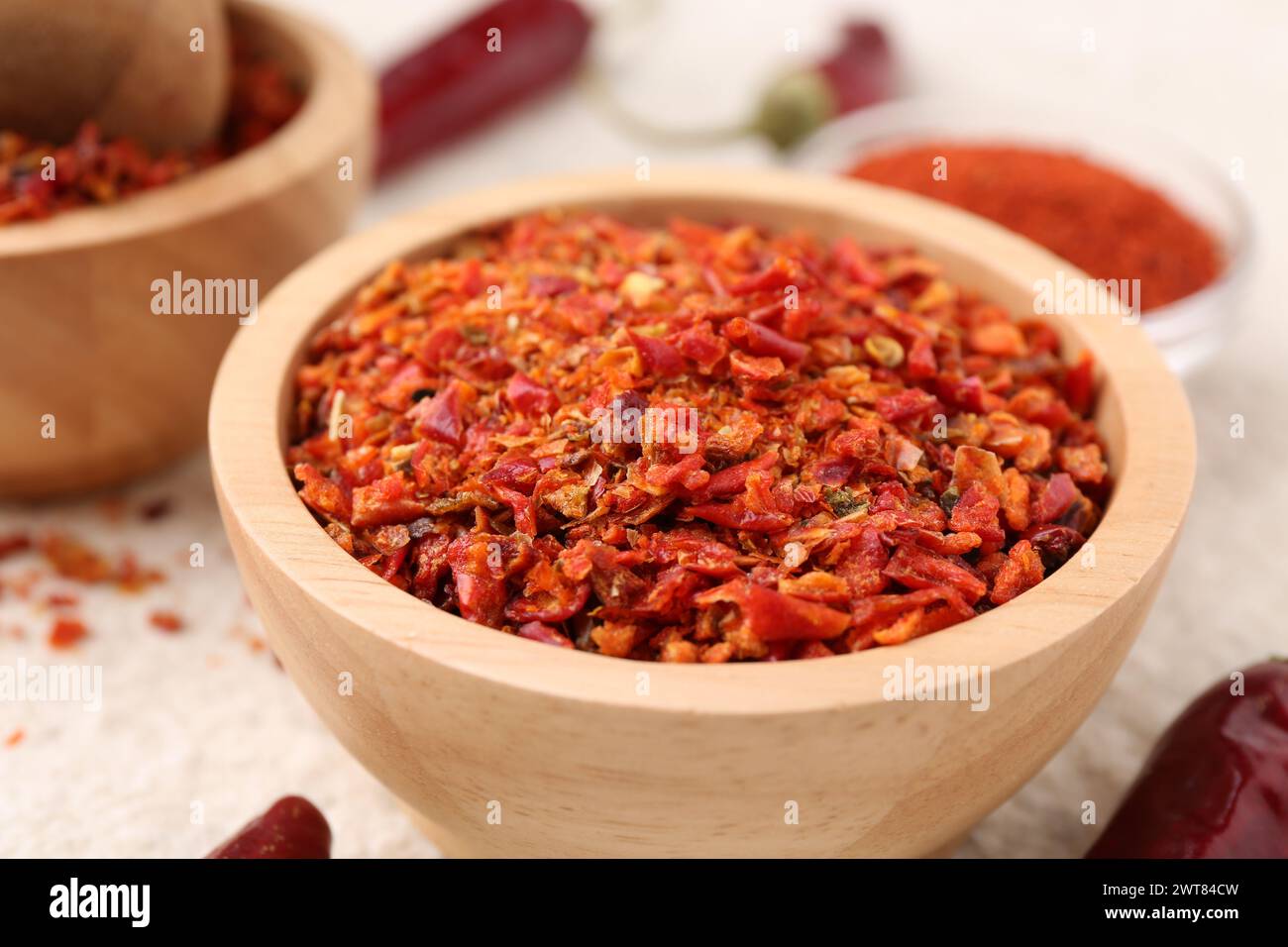 Chili pepper flakes and pods on light textured table, closeup Stock ...