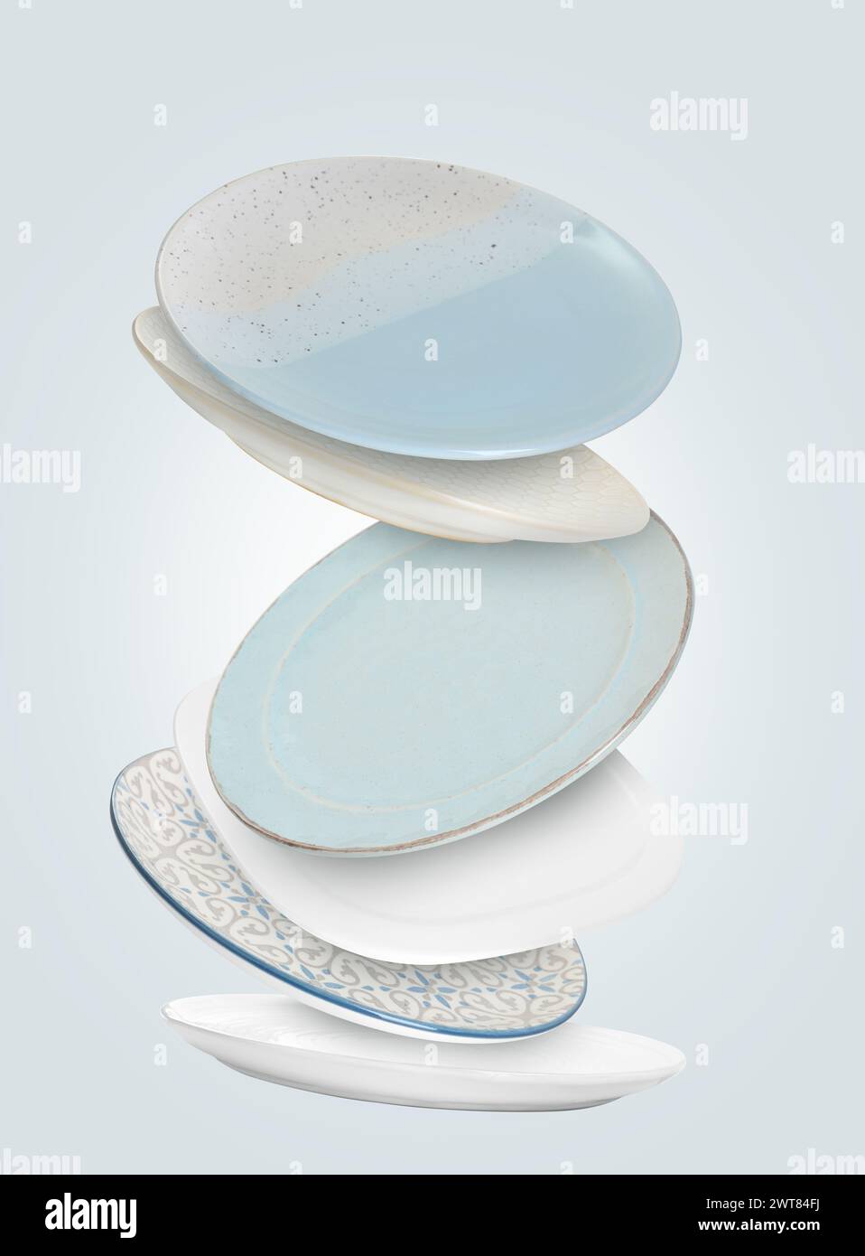Clean plates falling on light blue background Stock Photo - Alamy