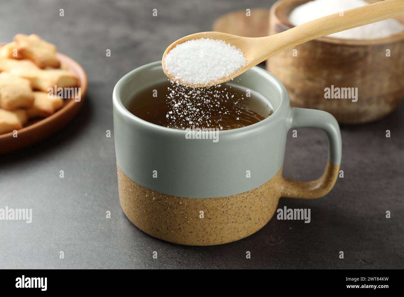 Adding sugar into aromatic tea at grey table, closeup Stock Photo - Alamy