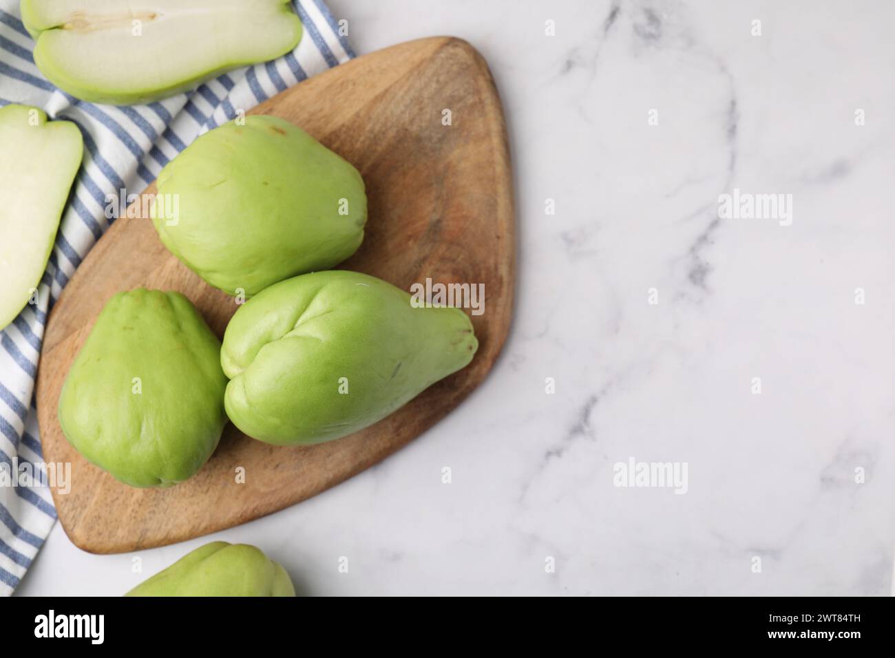 Fresh green chayote on light marble table, top view. Space for text ...