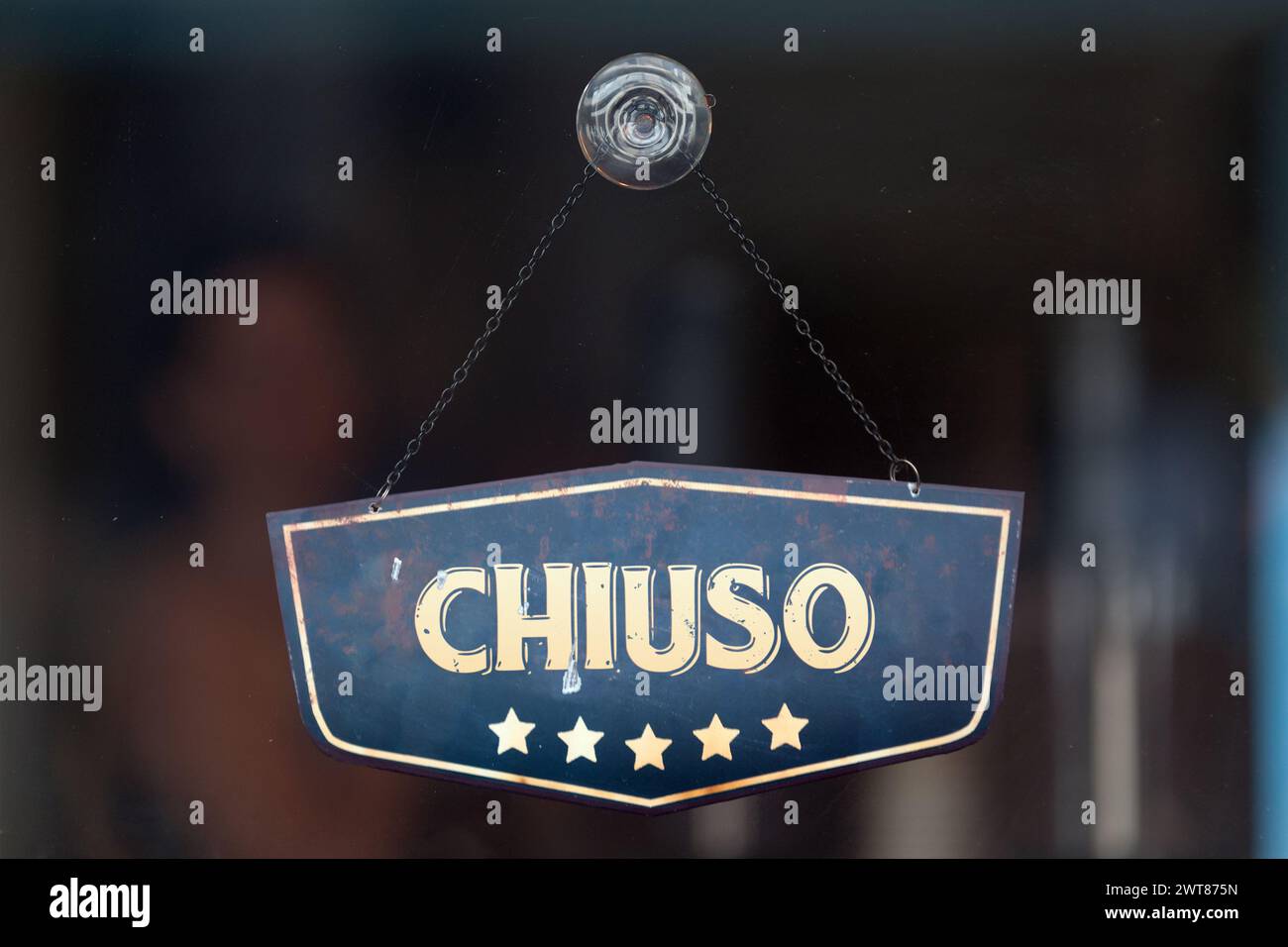 Old fashioned sign in the window of a shop saying in Italian "Chiuso ...