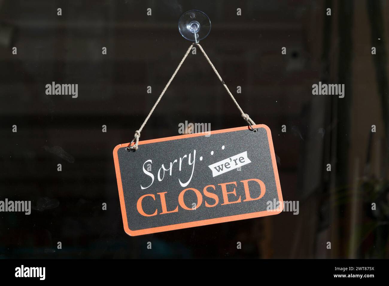 Black and orange sign hanging at the glass door of a shop saying "Sorry ...