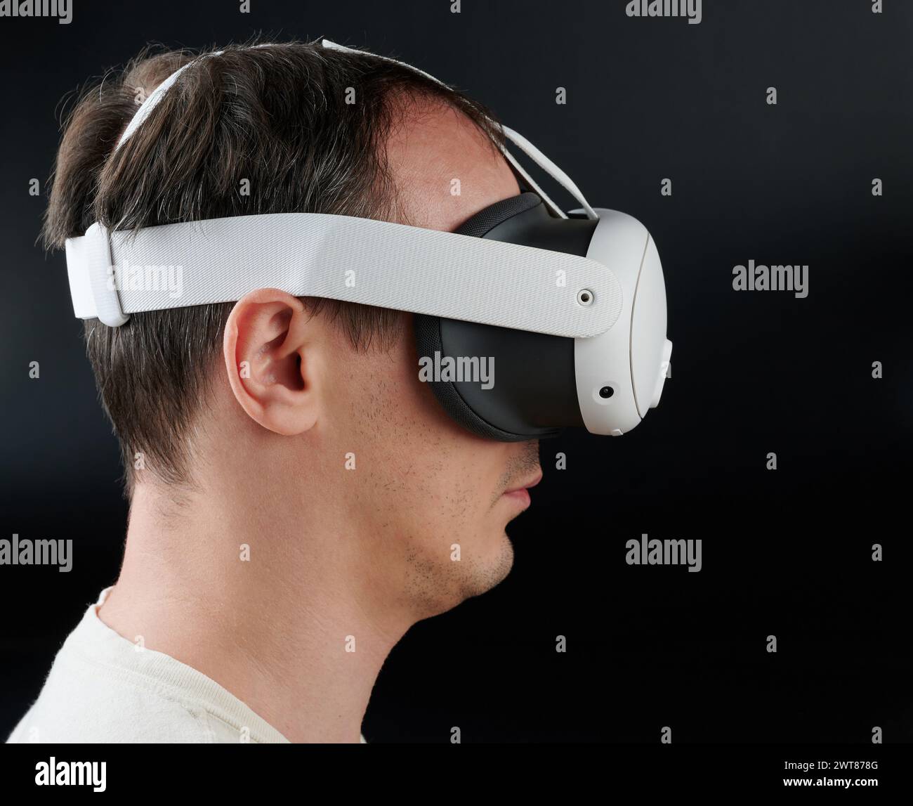 Profile portrait of man in VR headset isolated on black studio ...