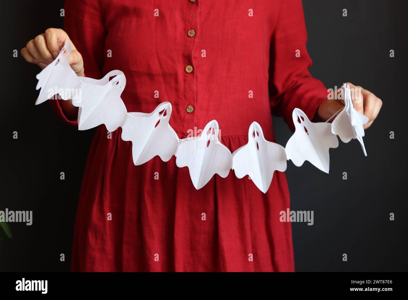 Woman in red dress holds white paper ghost garland. Halloween ...
