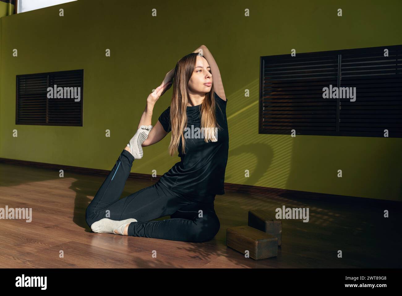 Attractive young woman performing Eka Pada Rajakapotasana exercise with ...