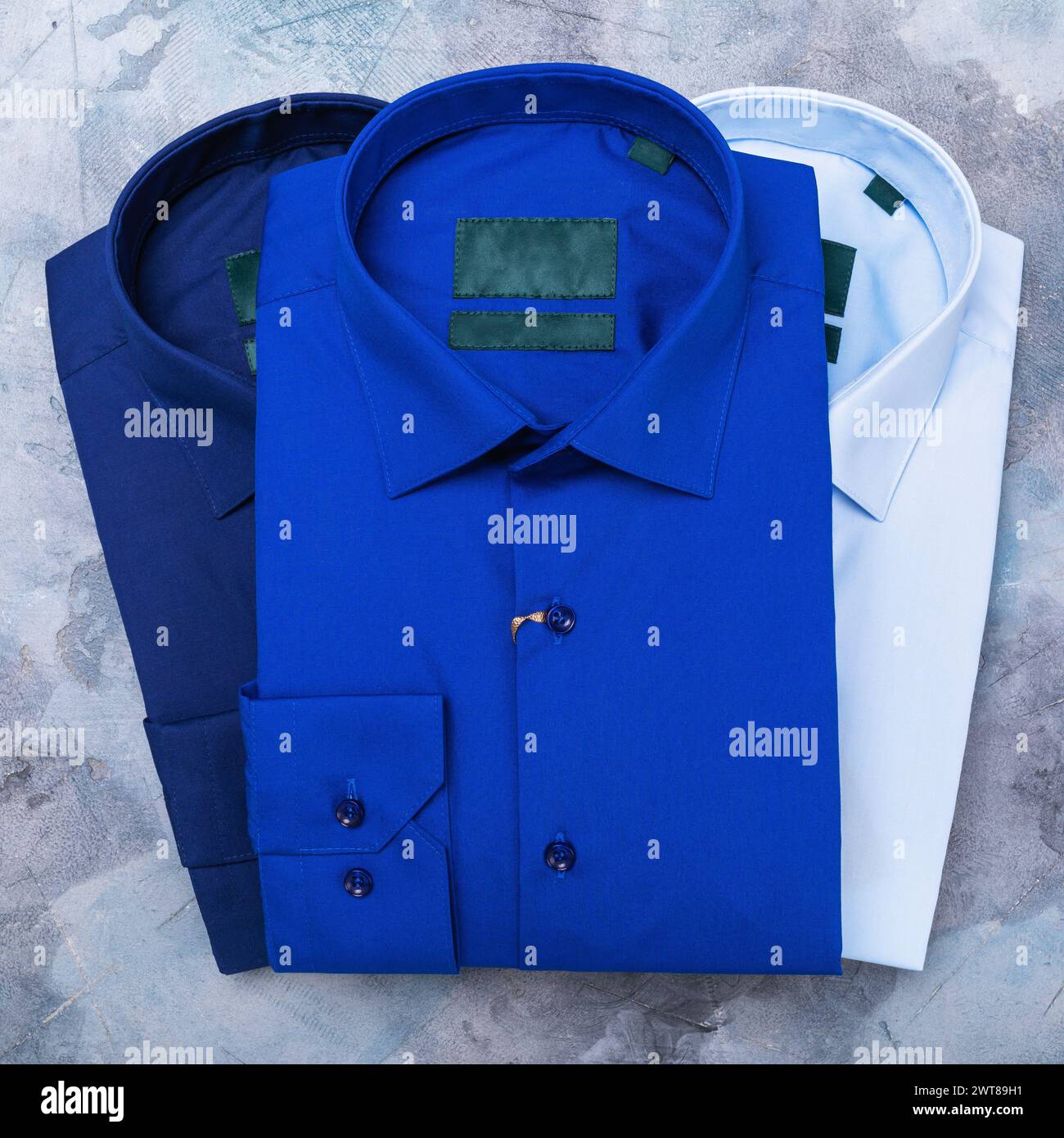 Three blue shirts of different shades on an abstract background, top ...