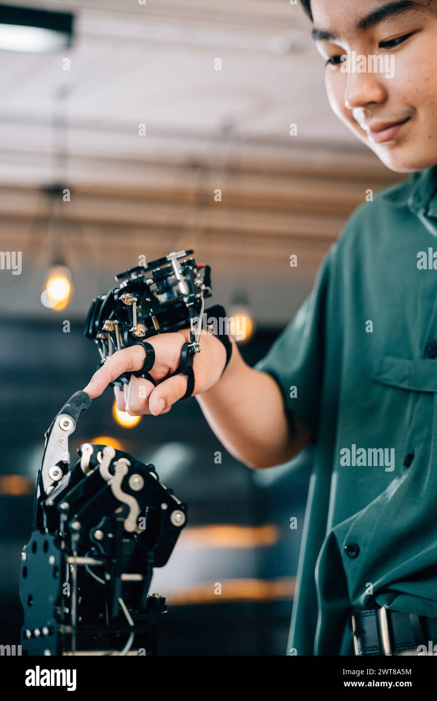 Teenage boy explores technology testing a robot hand and arm in a ...