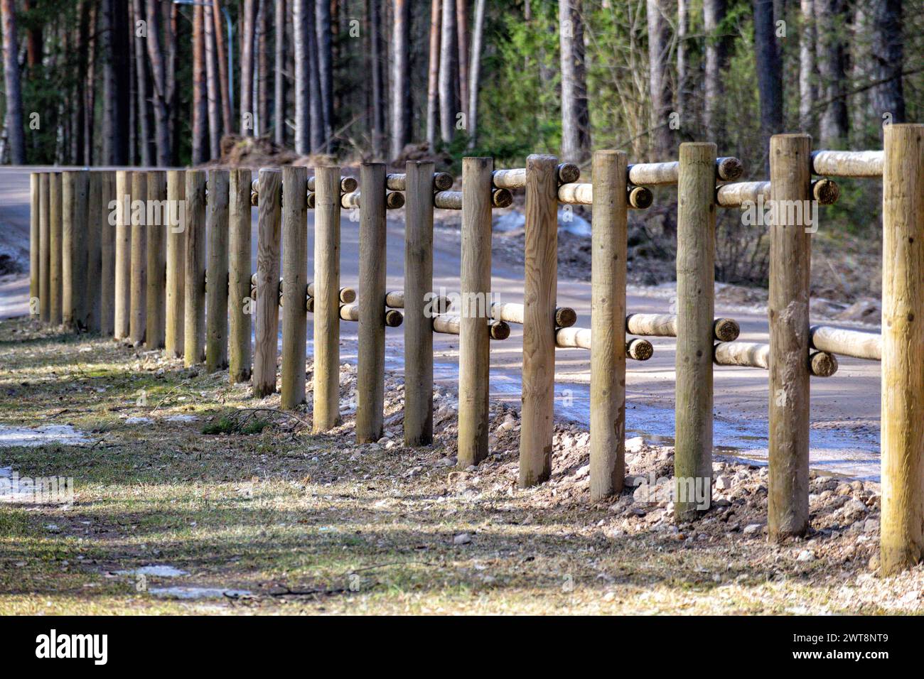 Round wooden post fencing between the gravel road and the grass ...