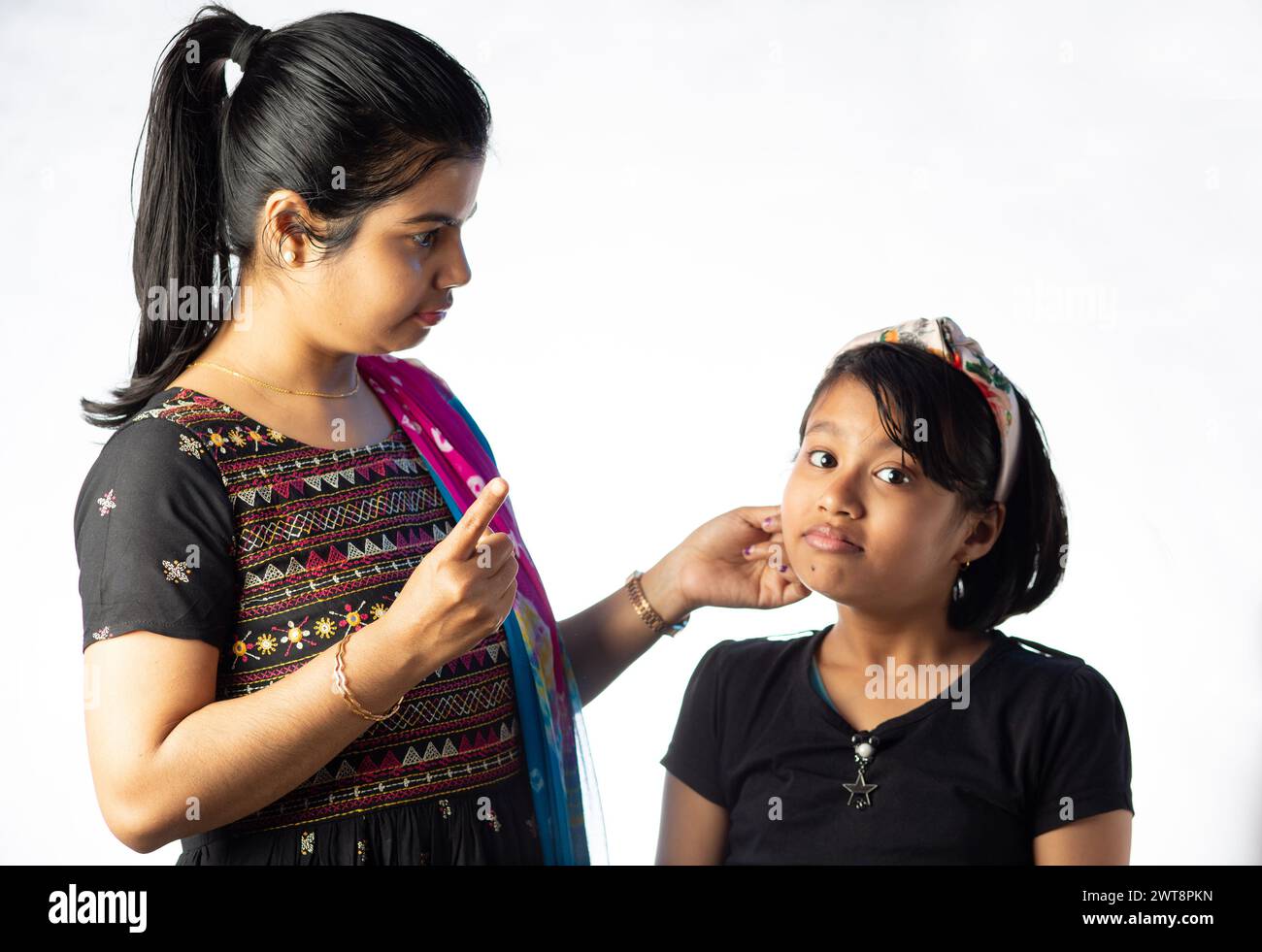 An Indian mother scolding and pulling her daughter's ear on white ...