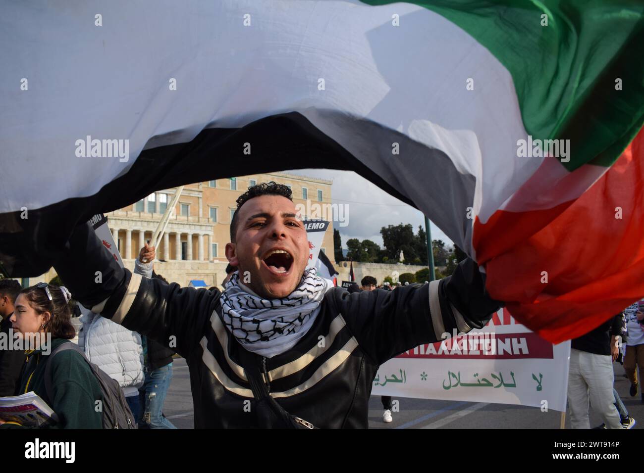 Athens, Greece. 16 March 2024. A man waves a Palestinian flag shouting ...