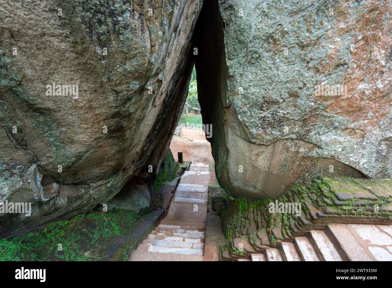 Tourists navigating the crevice between two large rocks at the exit of ...