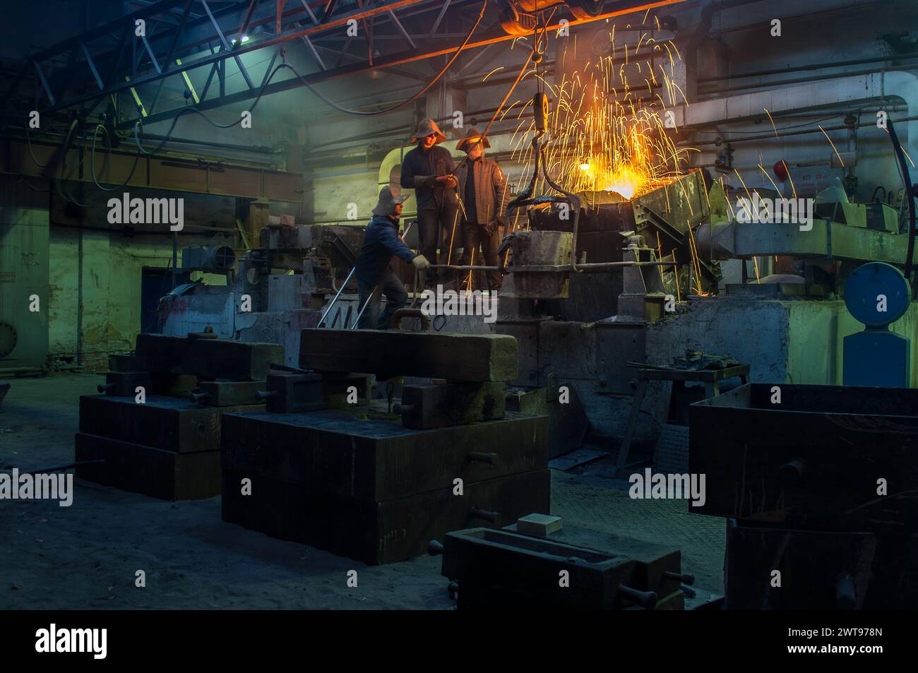 Industrial workers in protective gear casting metal in foundry. Team ...